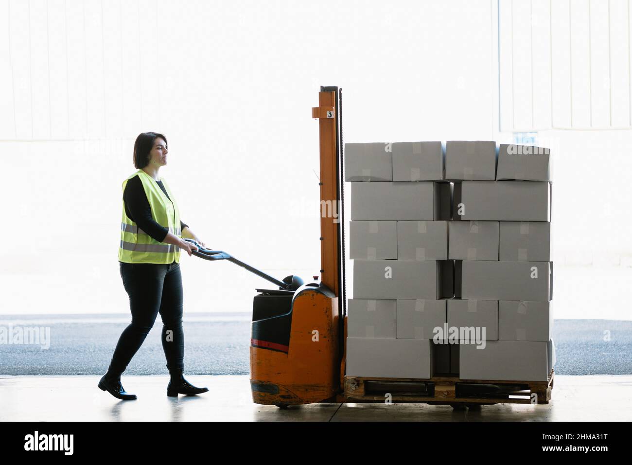 Full body side view of warehouse female worker in uniform high vis vest ...