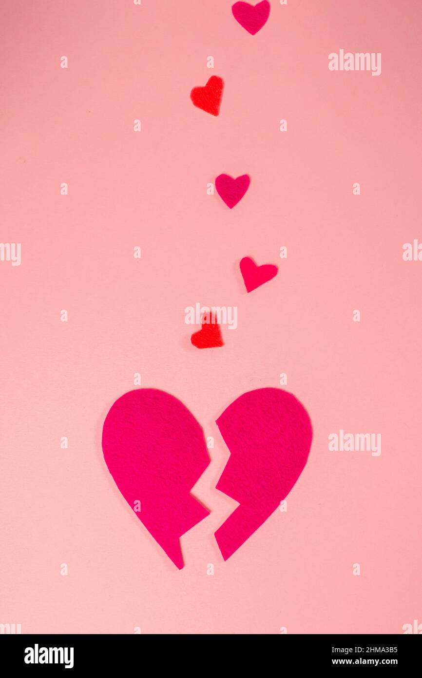 A broken heart. Felt heart divided into halves. Pink background ...