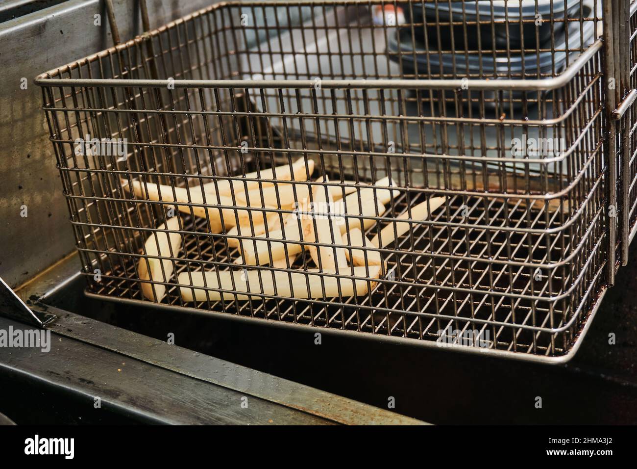 Side view of anonymous cook preparing French fries in deep fryer while ...