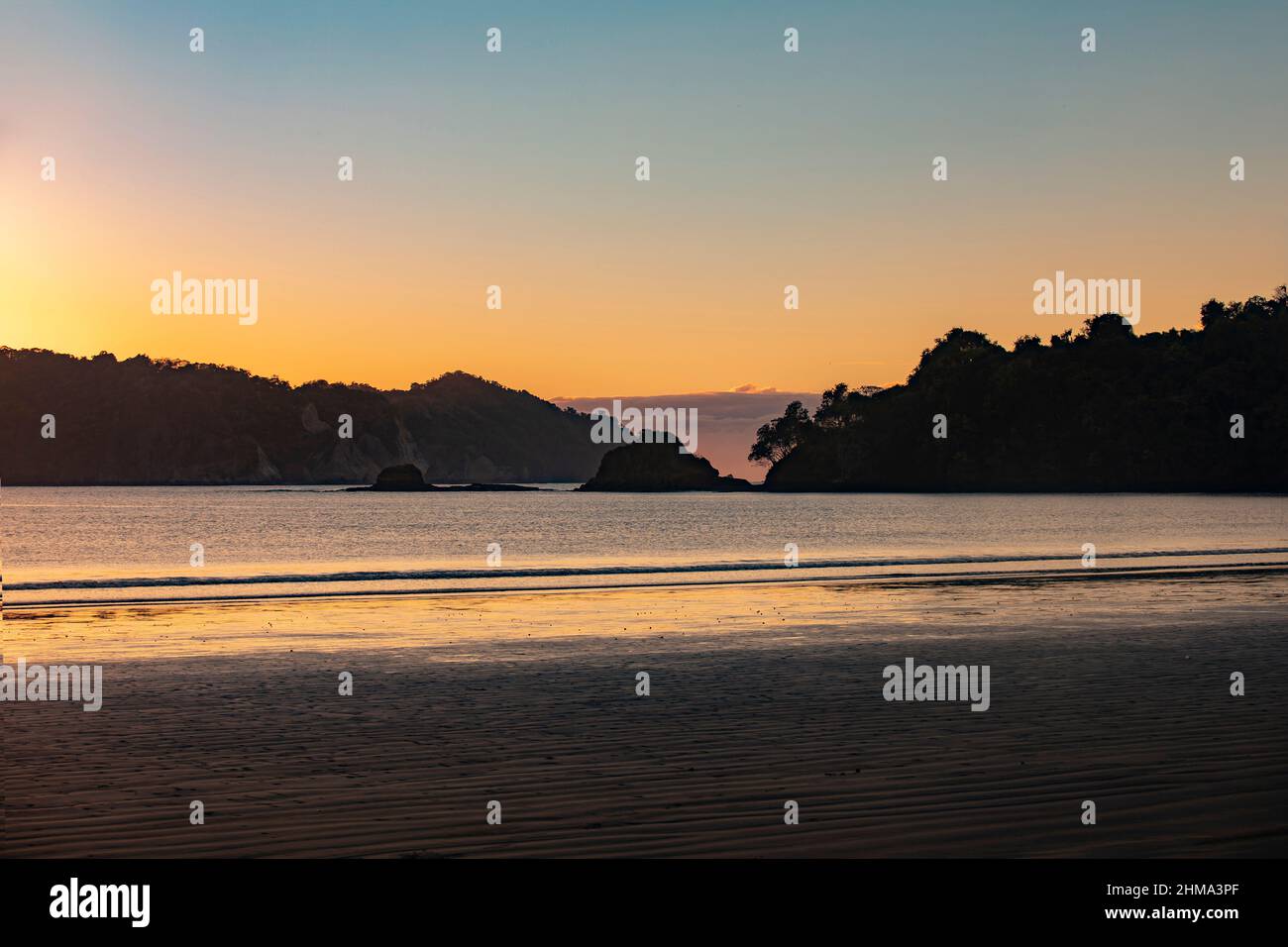 Rippling sea water with rocky cliffs covered with trees against cloudy ...