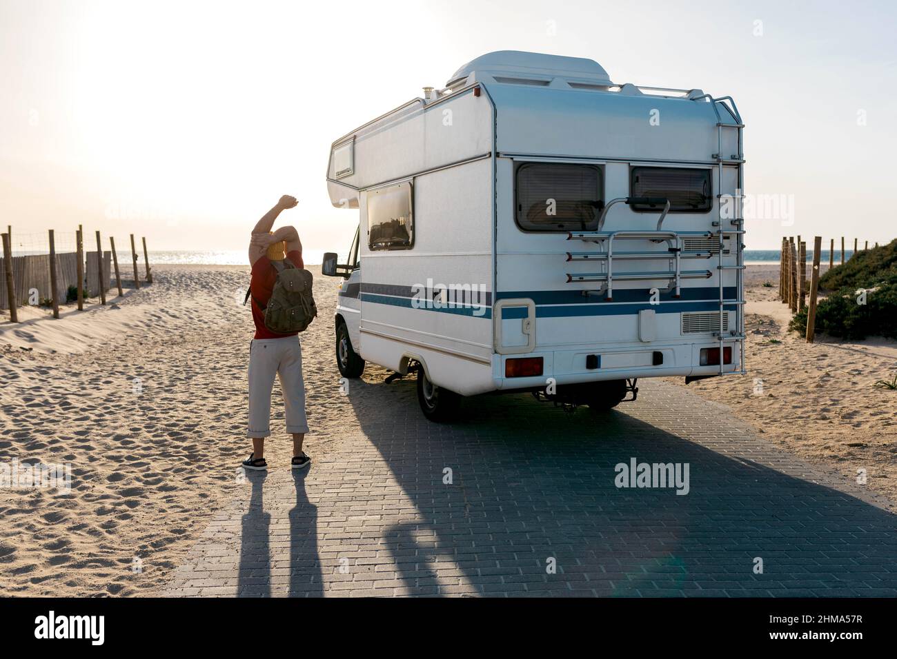 Back view of unrecognizable male adventurer standing with raised arms ...