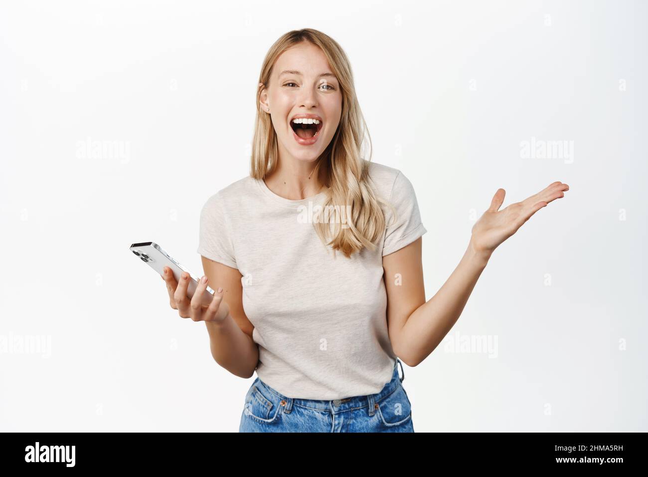 Happy blond girl winning on mobile phone app, watching smartphone and ...