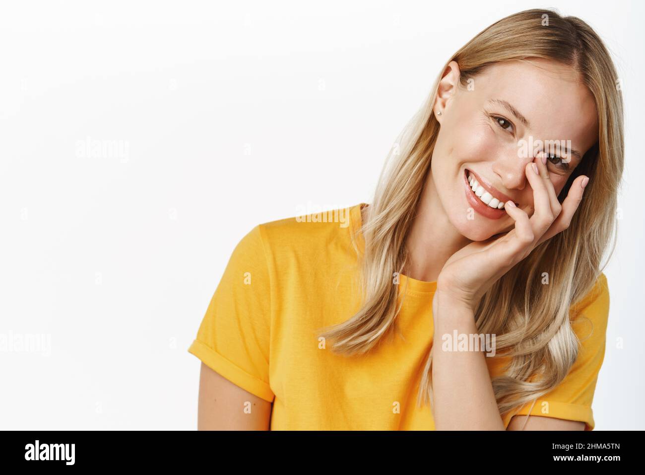 Portrait of happy blond woman laughing, smiling and looking authentic, touching clear glowing ...