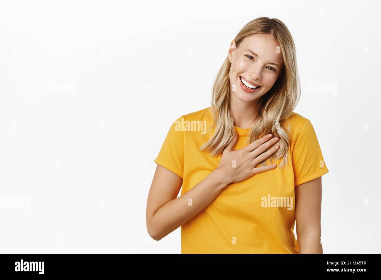 Smiling beautiful modern girl laughing, holding hand on heart ...