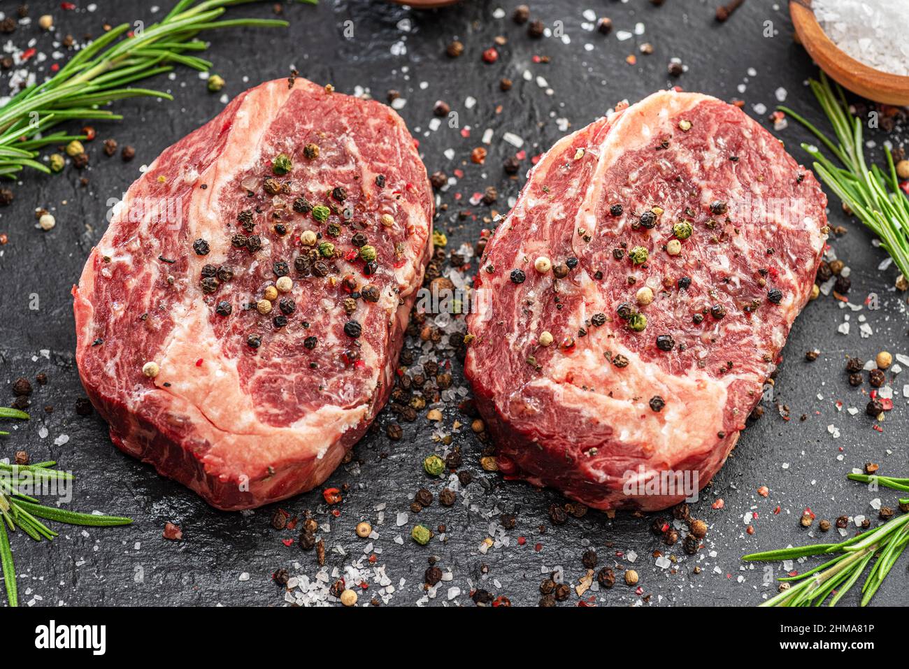 Raw Ribeye steaks with salt and herbs on grey board. Top view Stock ...