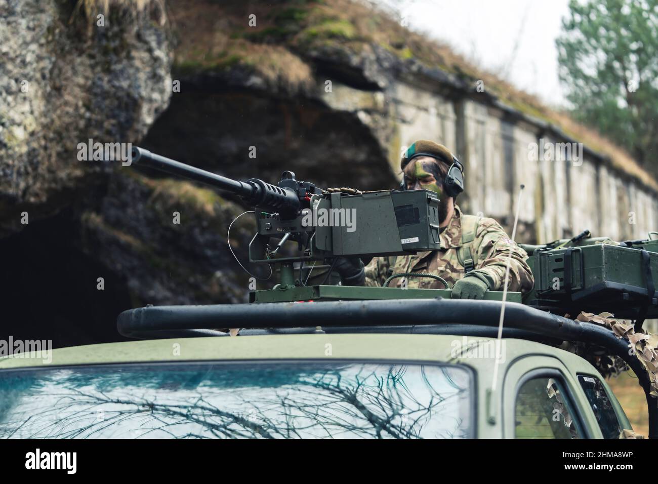 Bombarding machine gun gripped to a patrol unit army vehicle with ...
