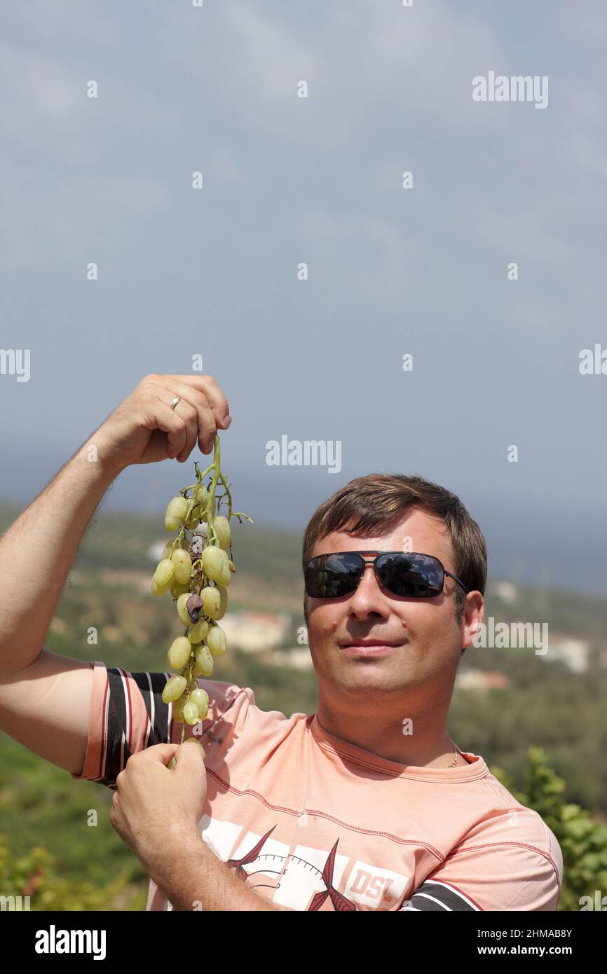 Man poses with vine in the vineyard, Crete Stock Photo - Alamy