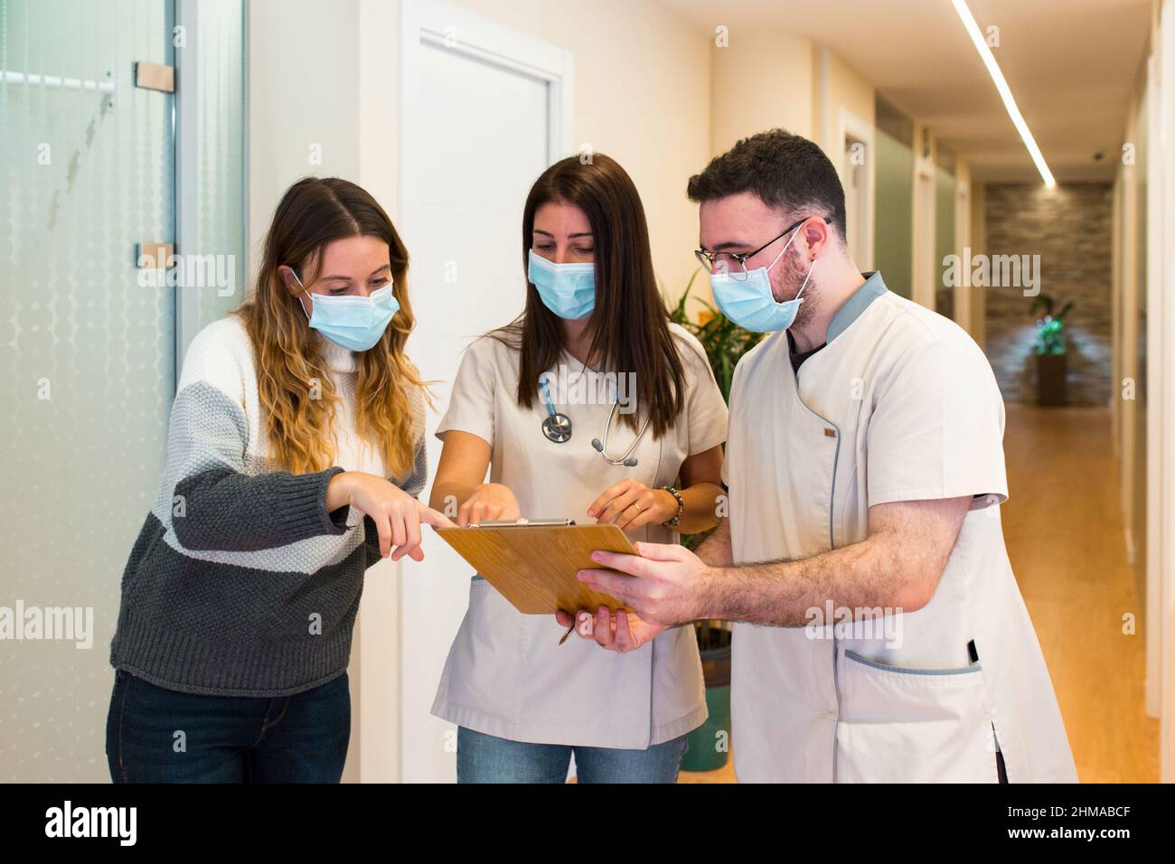 Female doctor and her medical assistant helping a patient to fill a ...