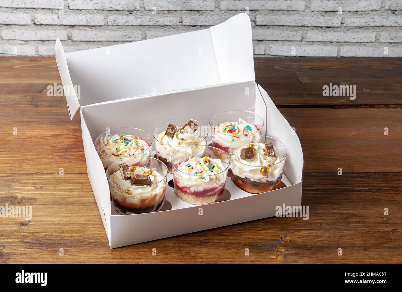 Box with assorted set of beautiful and delicious trifle cakes close-up ...