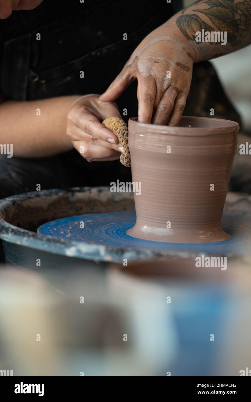 Hands forming a piece of clay into a pot on a pottery wheel Stock Photo ...
