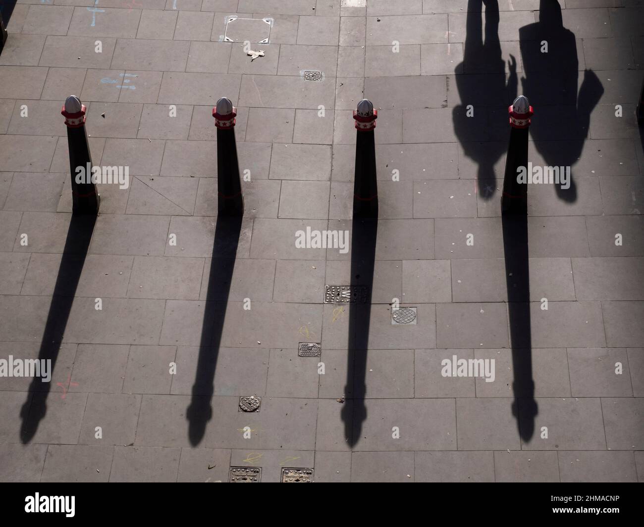 Shadows of Pedestrians walking through City of London bollards boundary ...