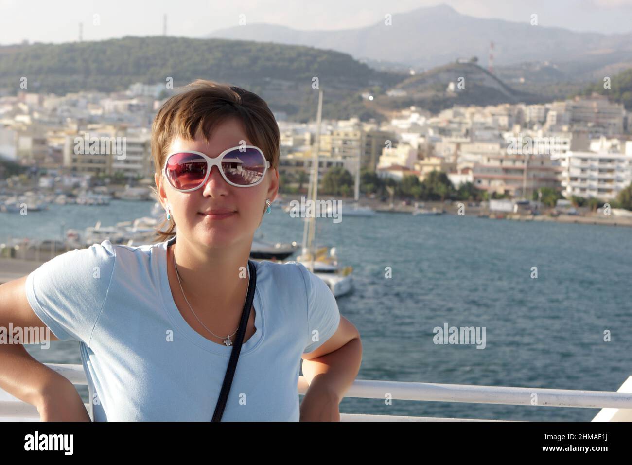 Woman poses on harbor of Retimo background, Crete Stock Photo - Alamy