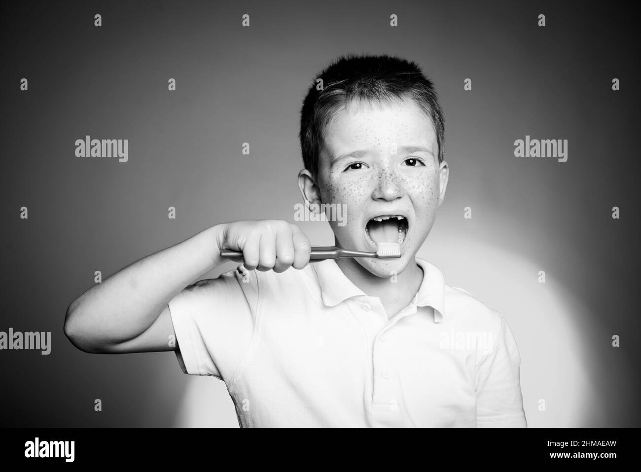 Smiling little boy child with toothbrush in hand isolated on blue ...
