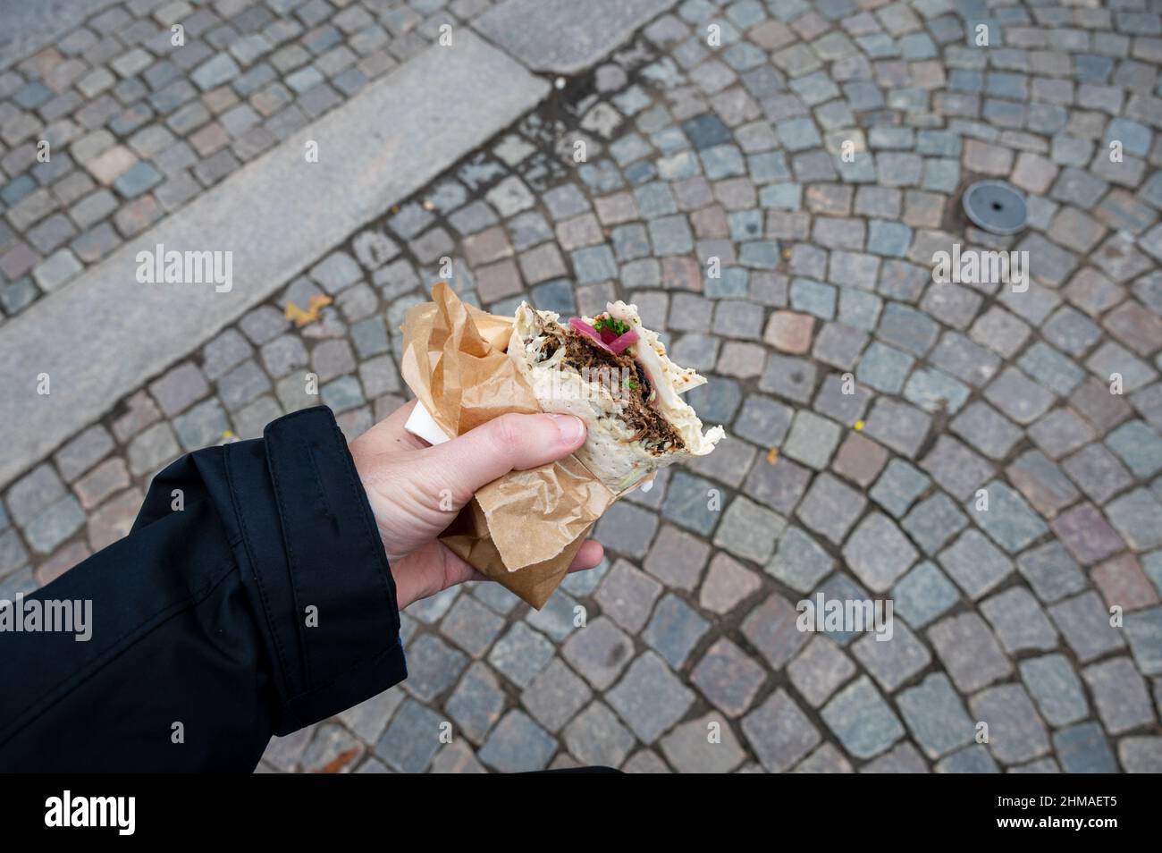 Human hand holding fast food eating on the street Stock Photo - Alamy