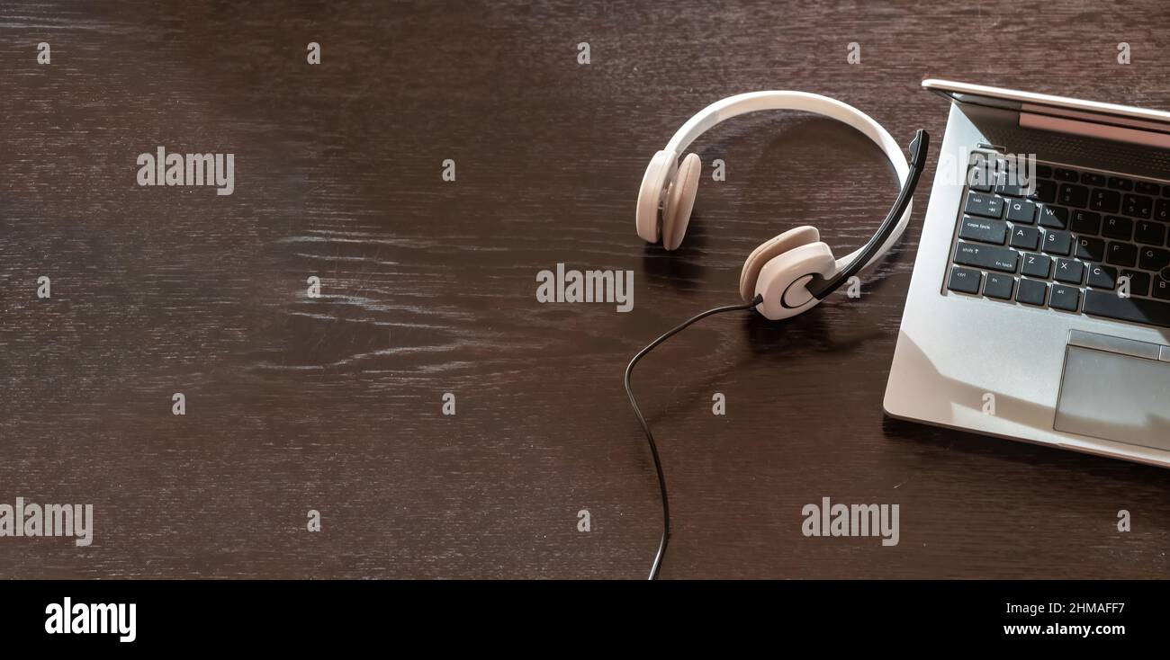 Home office, headset on a laptop, wooden table, view from above, copy ...