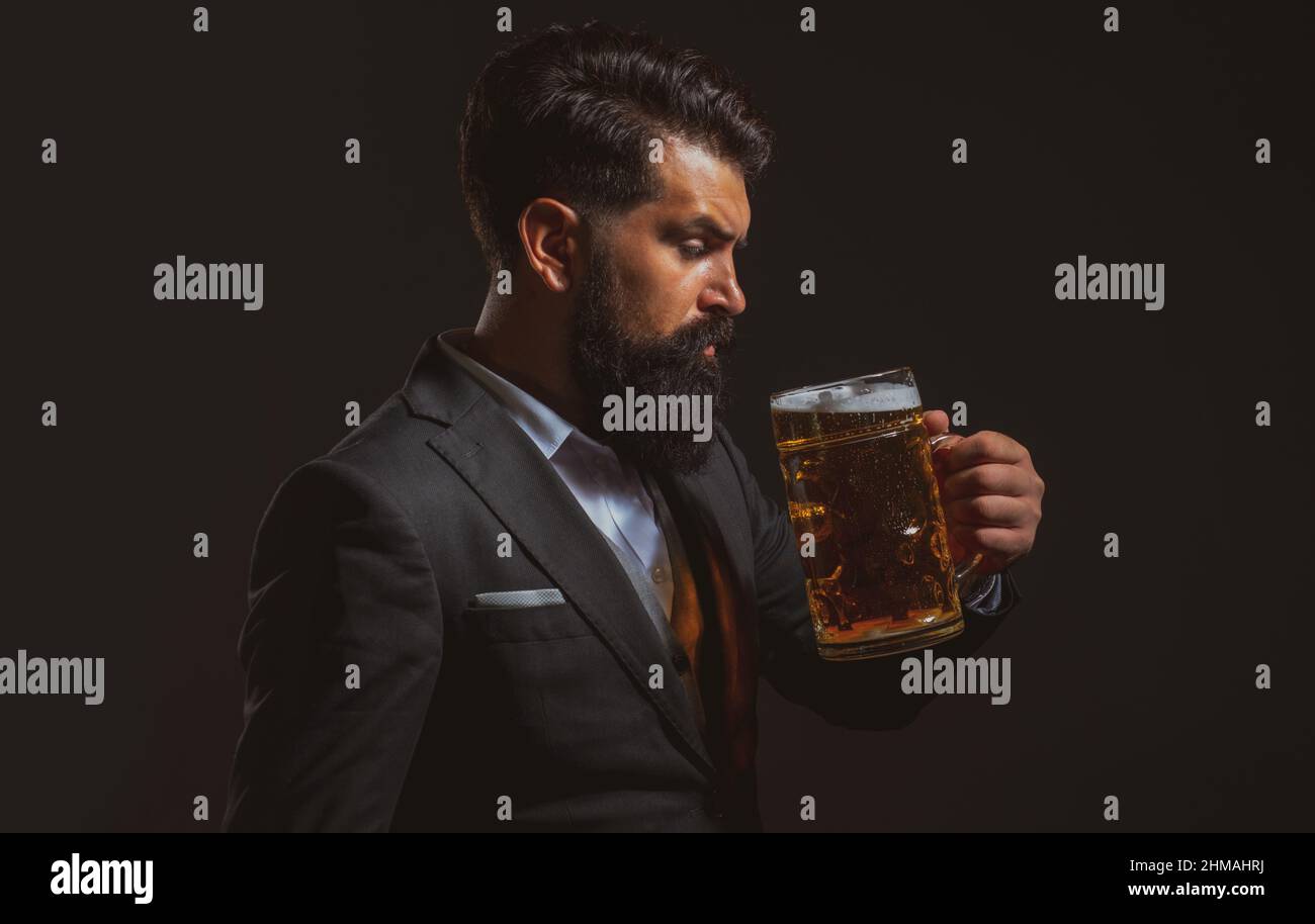 Man in classic suit drinking beer. Bearded guy in business outfit looks ...