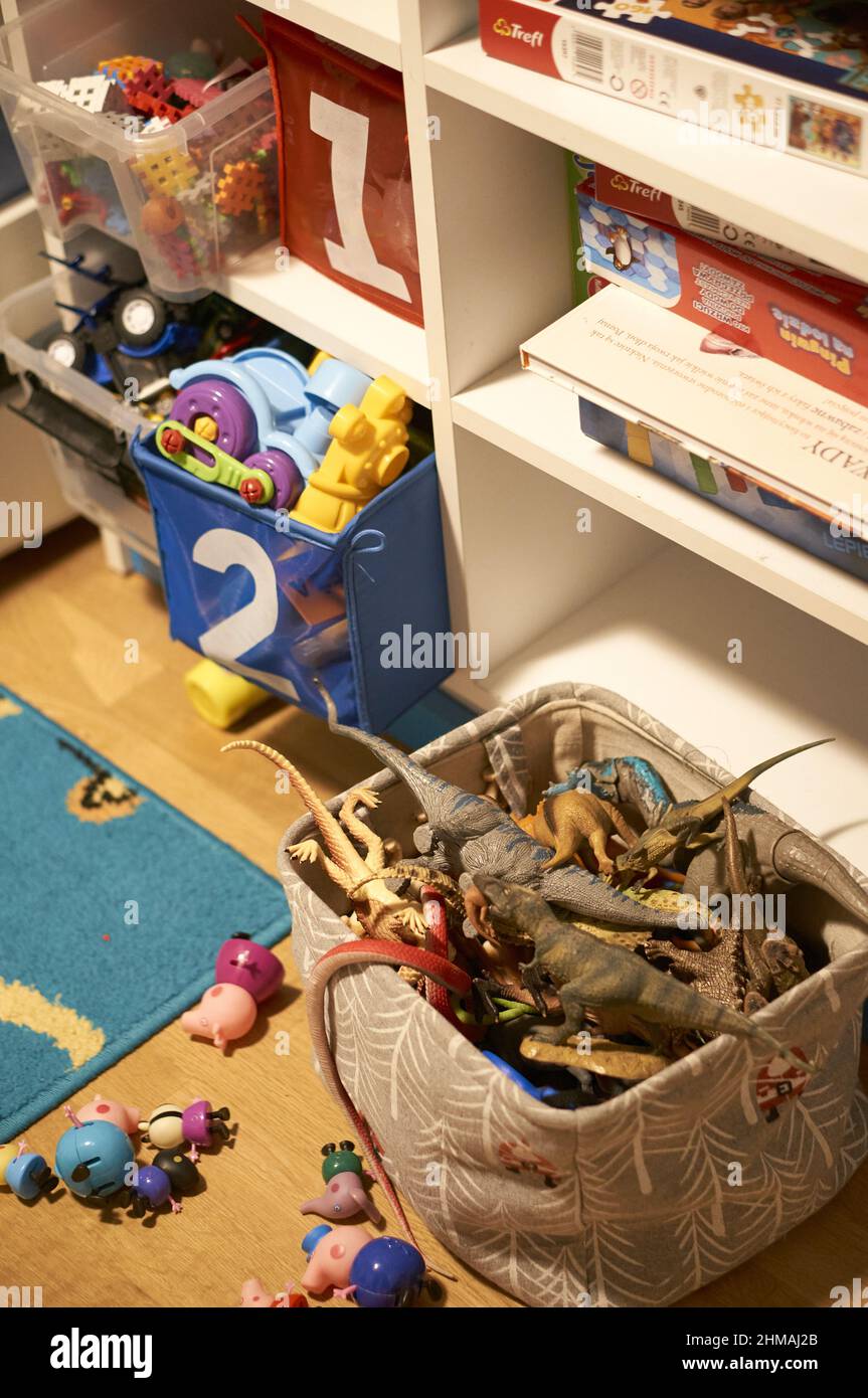 Vertical shot of a pile of toy dinosaurs in a box next to a furniture ...