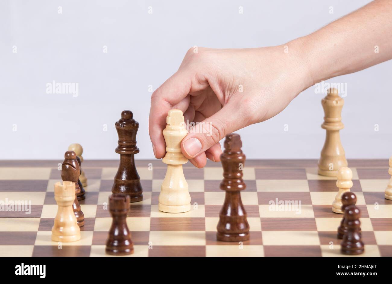 Person moving King Chess piece during a game with light background ...