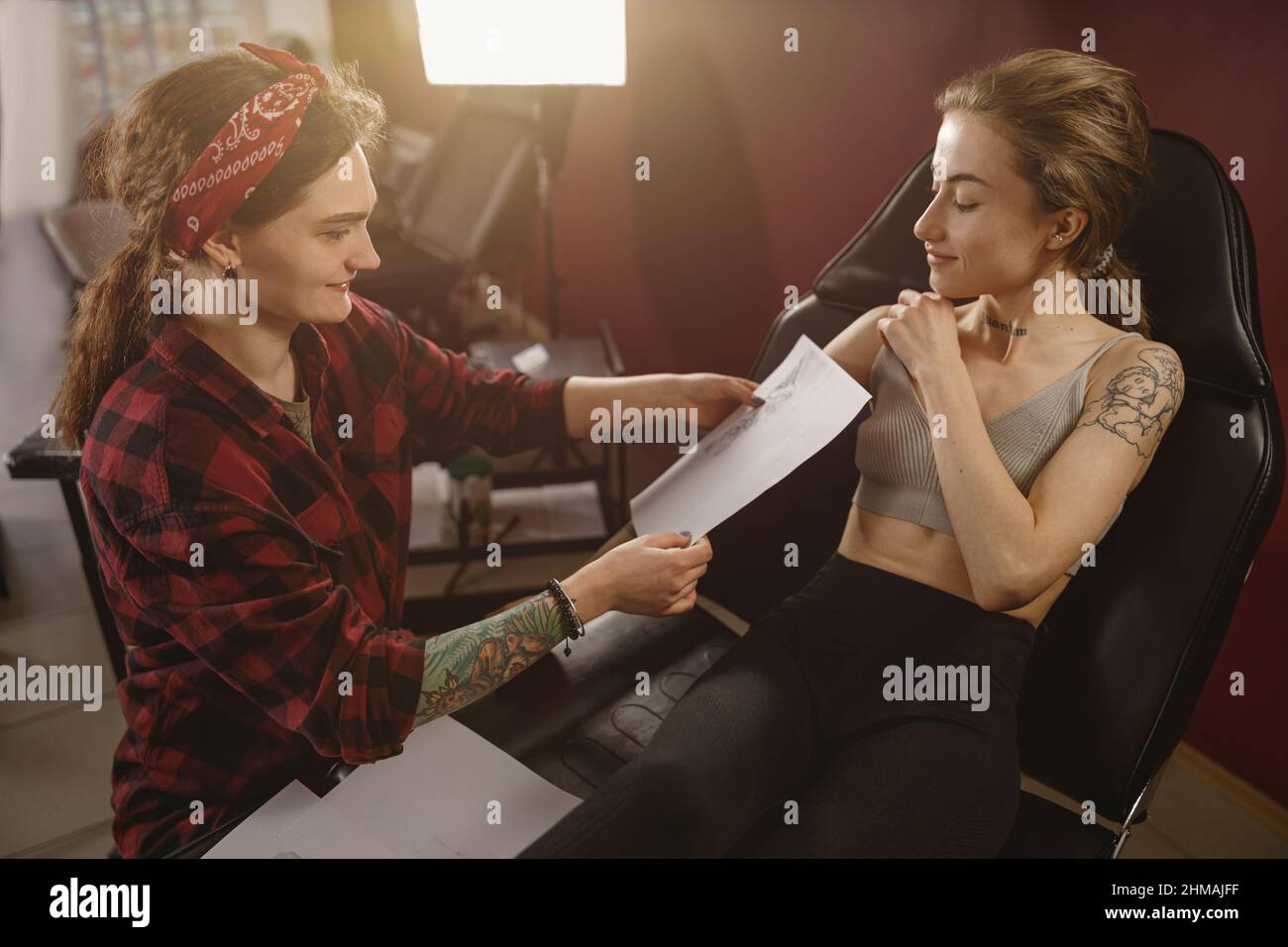 Woman master applying paper with pattern to client hand Stock Photo - Alamy