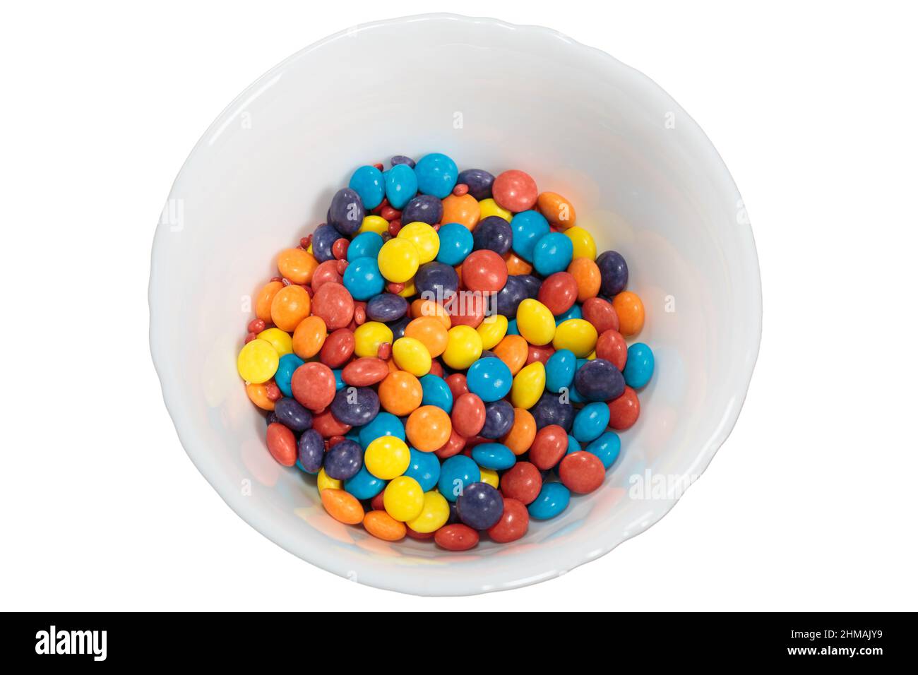 Colorful sugar dragee in white round bowl. It is isolated over white ...