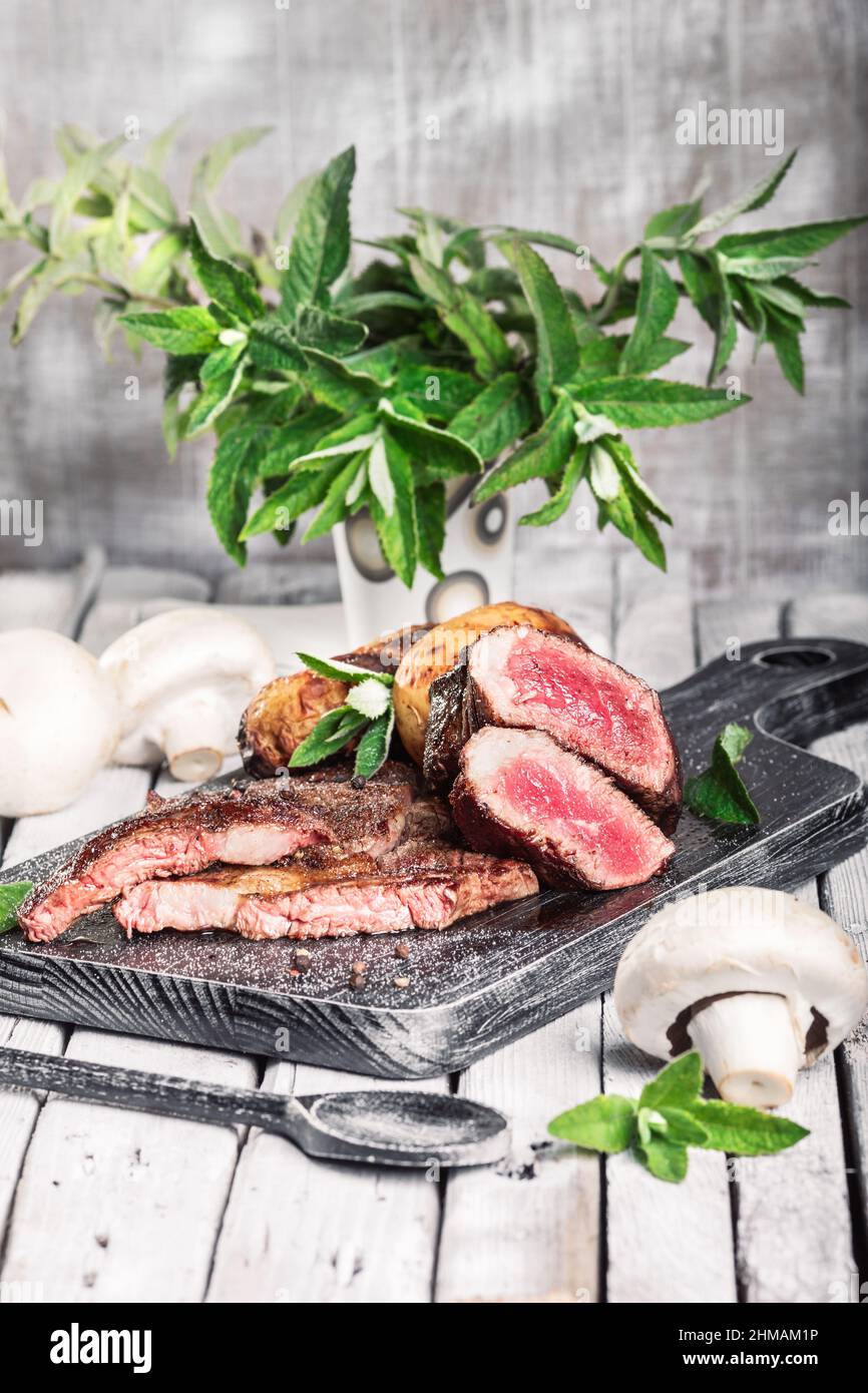 Selection of medium rare steaks, cut with knife with potato wedges as ...