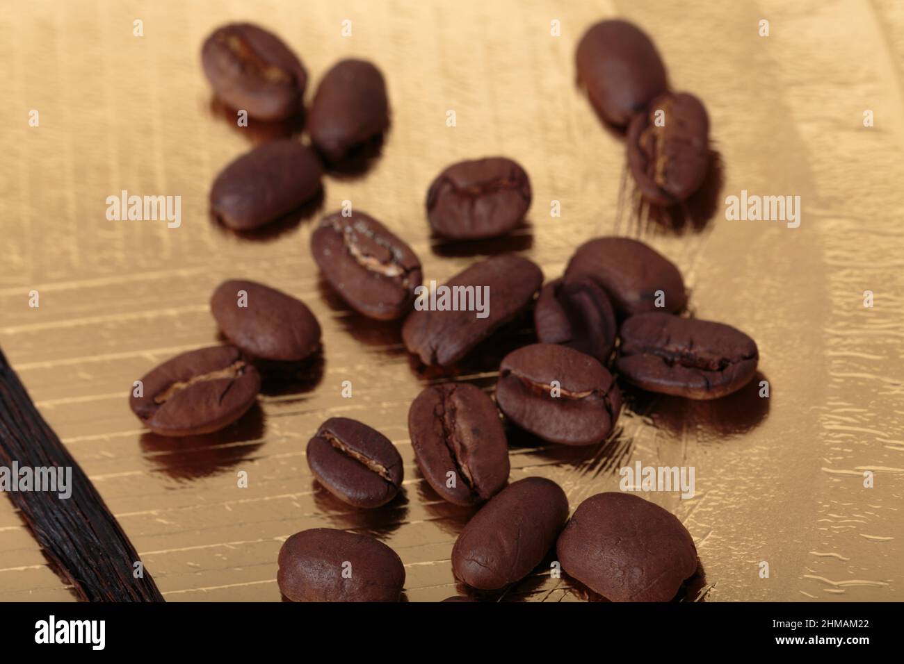 Roasted coffee beans on a golden surface. Close-up. There is a small ...