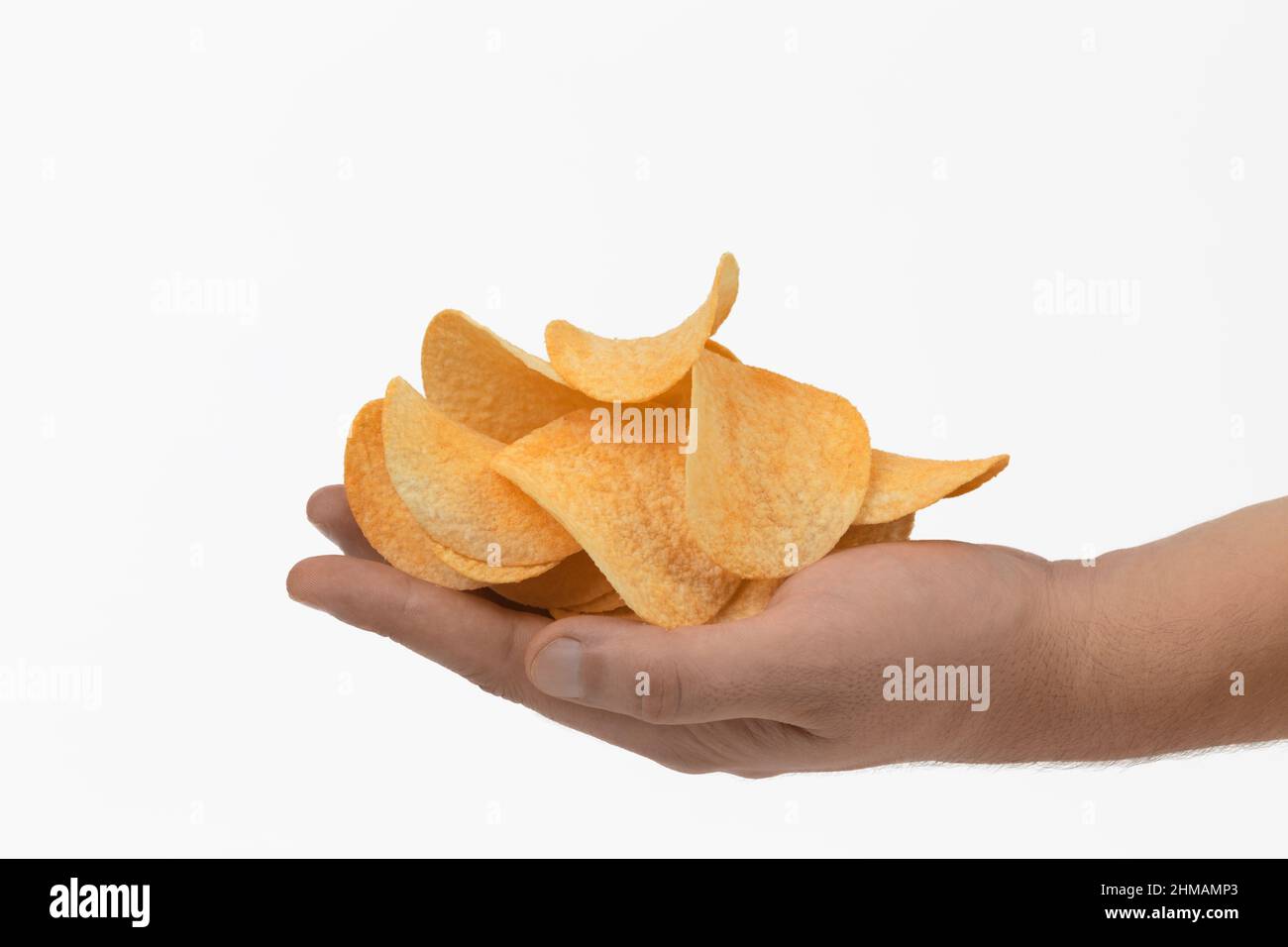 A human hand holds potato chips. It is isolated over white background ...