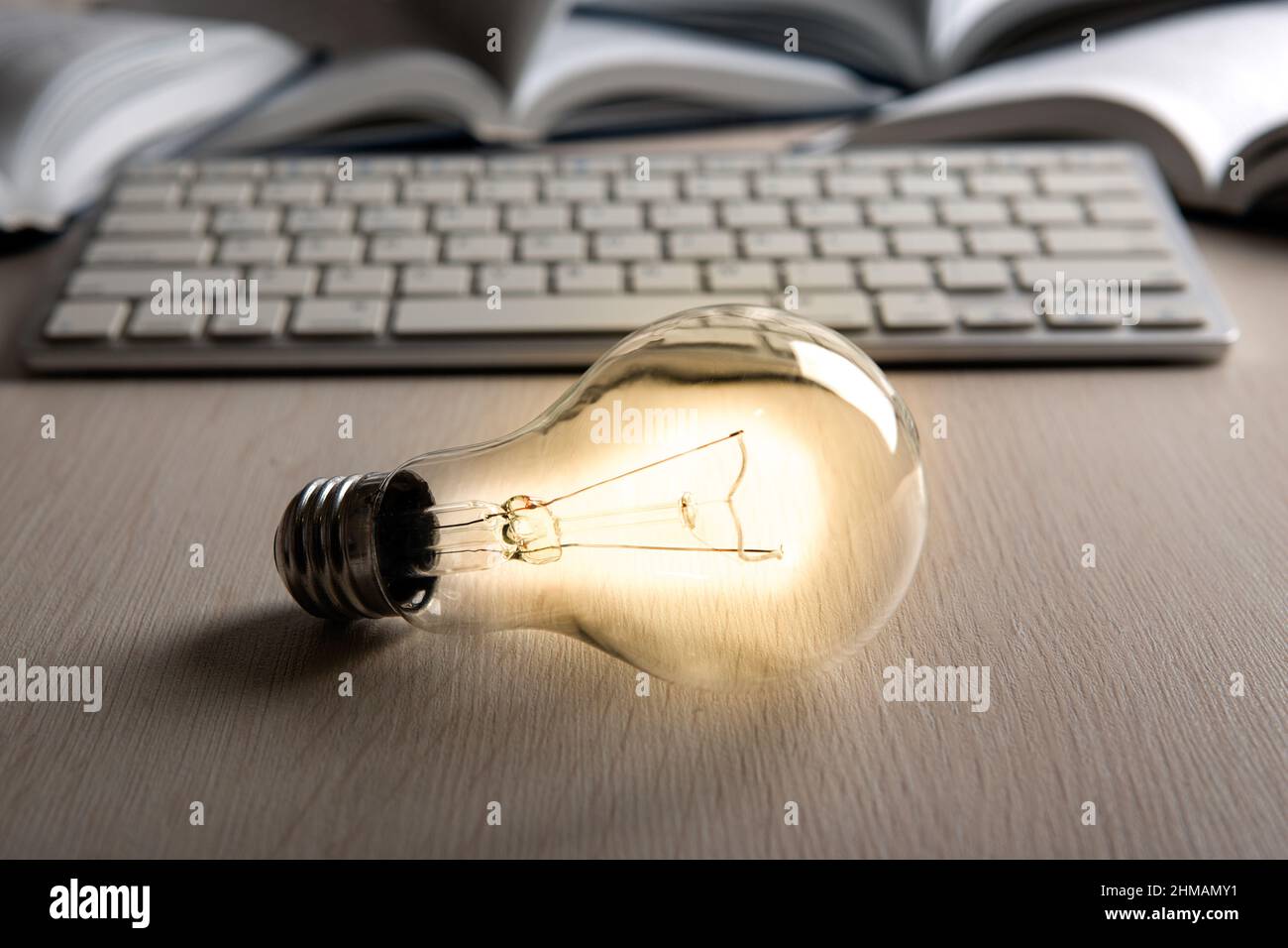 burning glass bulb on the background of books and pc keyboard Stock ...