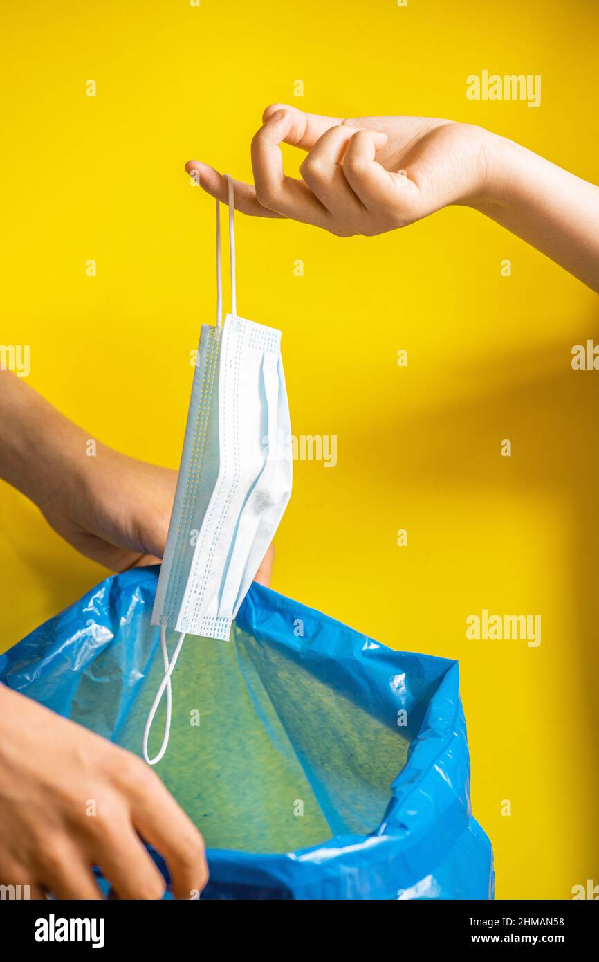 Person's cropped hand throw the mask in the trash bag. To show lift a ...