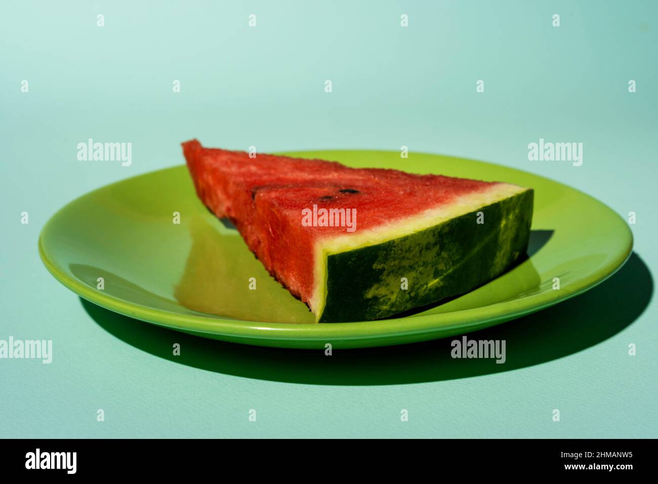 watermelon slice on a plate on a turquoise background, side view Stock ...
