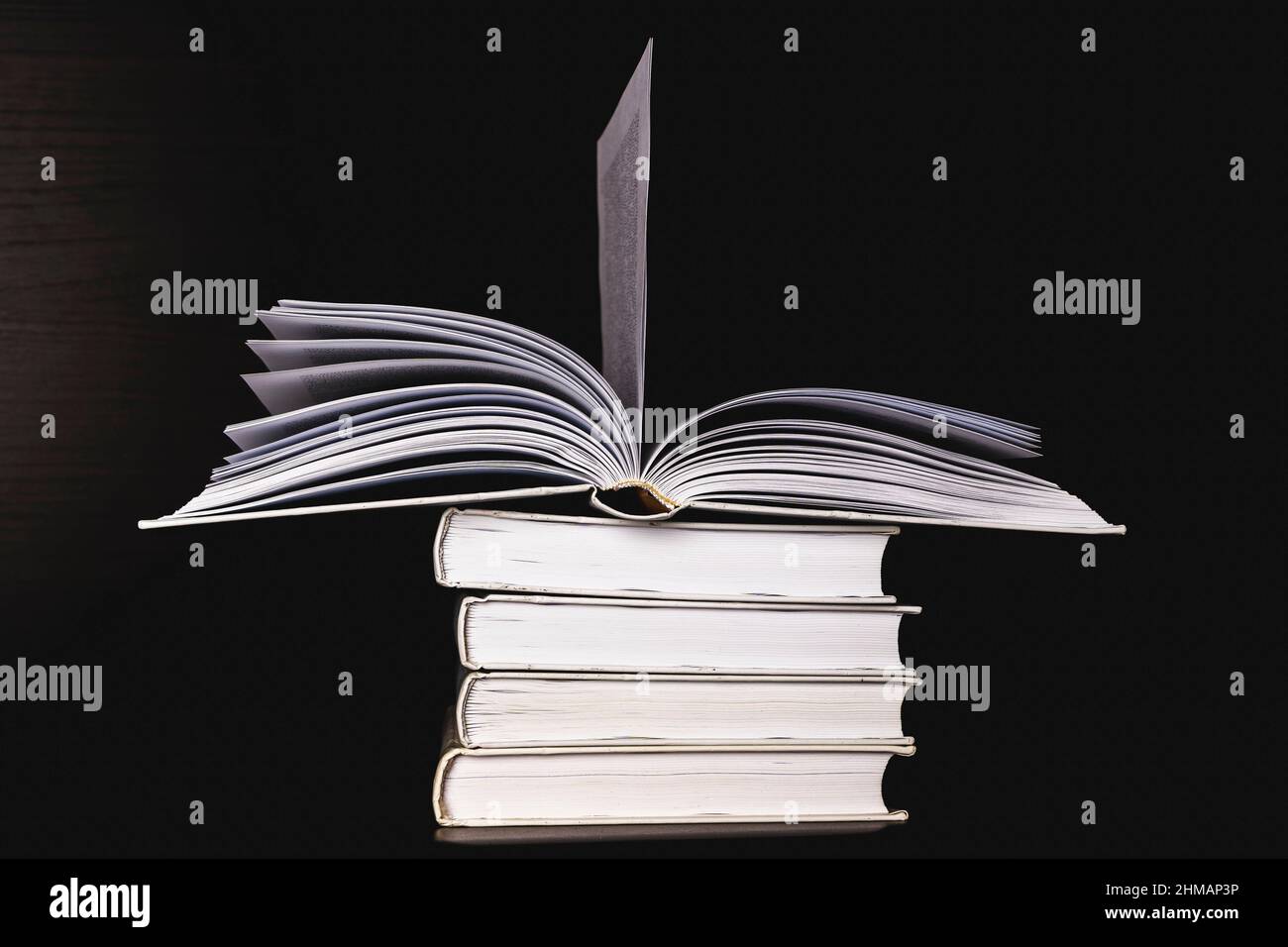 A stack of white blank books on a shelf on a black background, the top ...