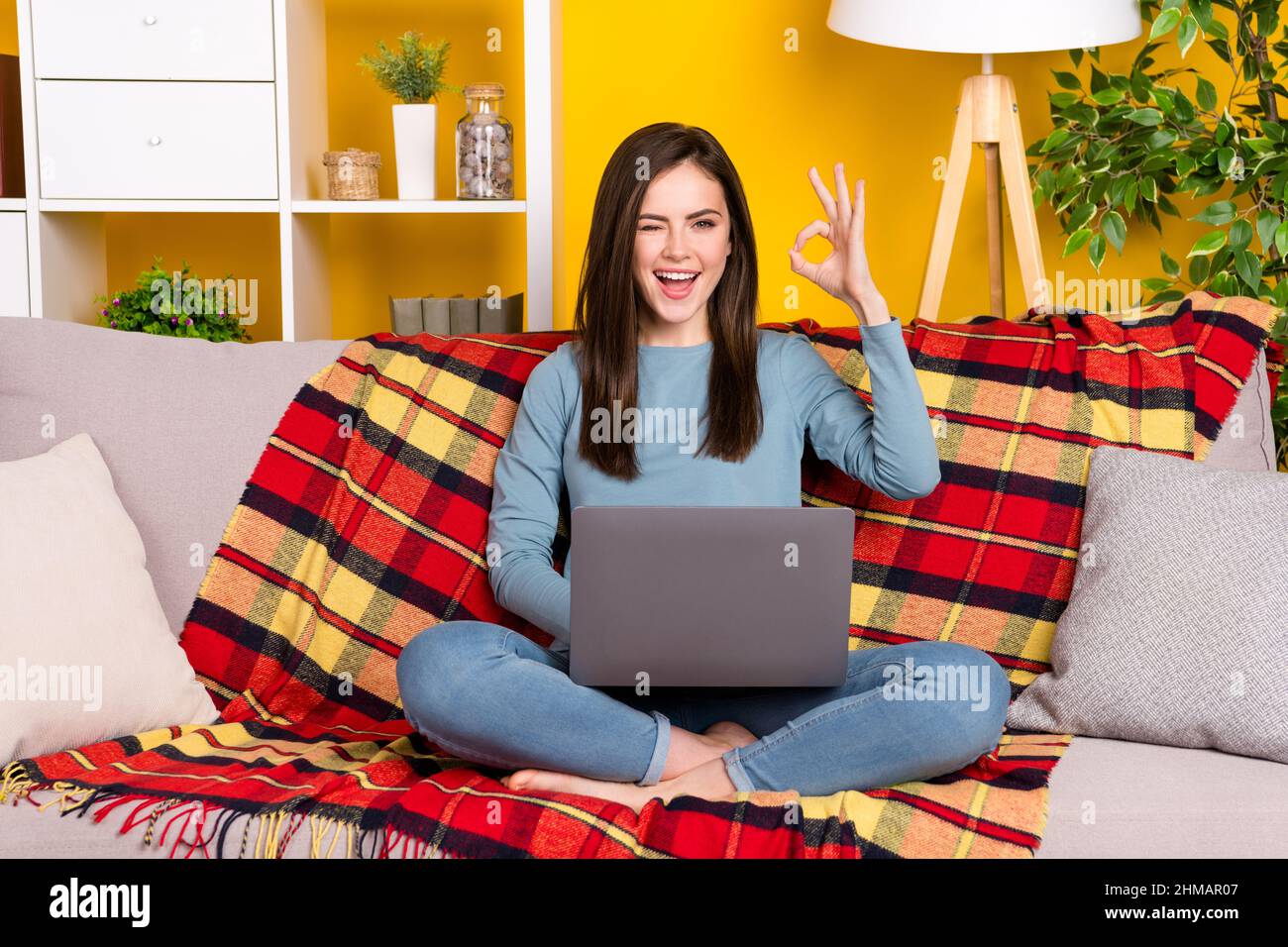 Full body photo of attractive funny person sit couch eye wink show okey ...