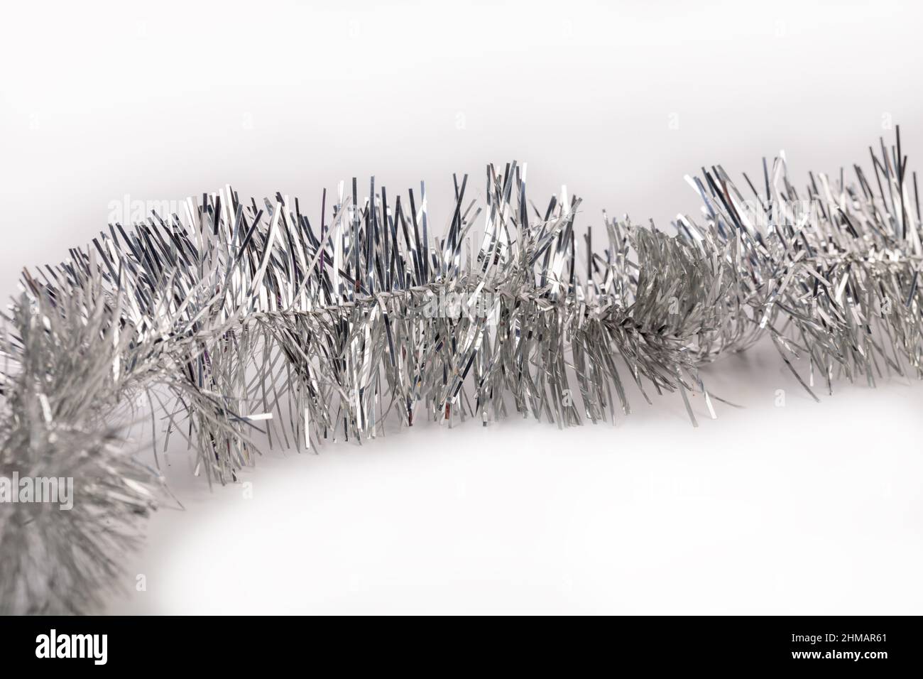Silver Christmas tinsel with stars. It is located on a white surface ...
