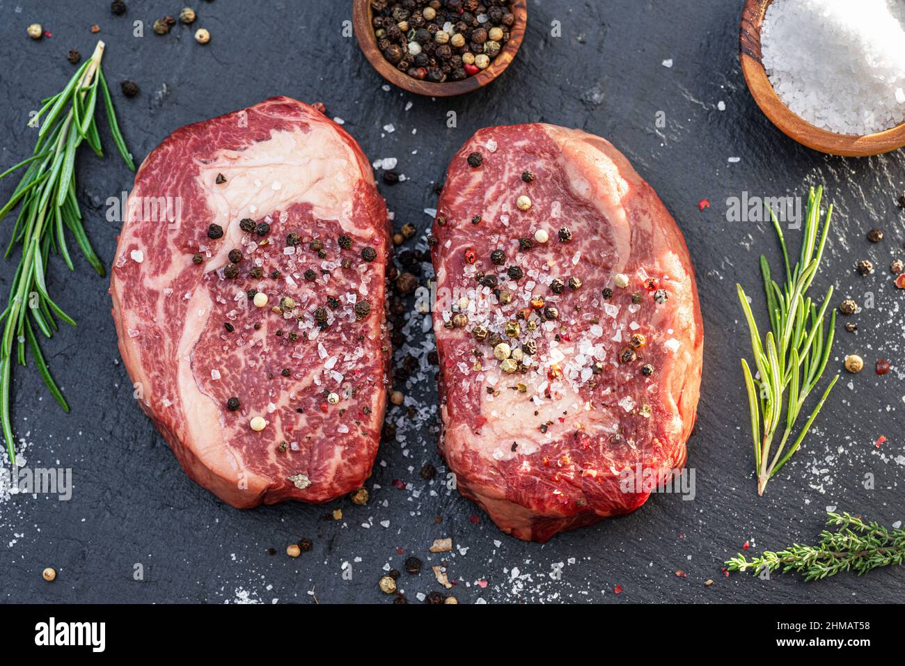 Raw Ribeye steaks with salt and herbs on grey board. Top view Stock ...