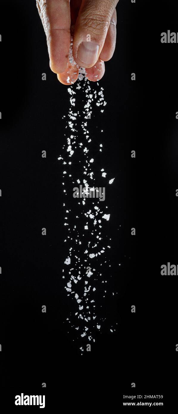 Male hand sprinkling edible salt at black background Stock Photo - Alamy