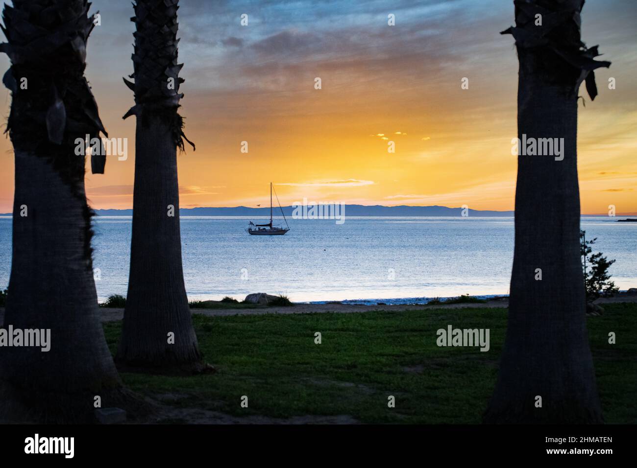 Sail boat view from shore during sunset Stock Photo - Alamy