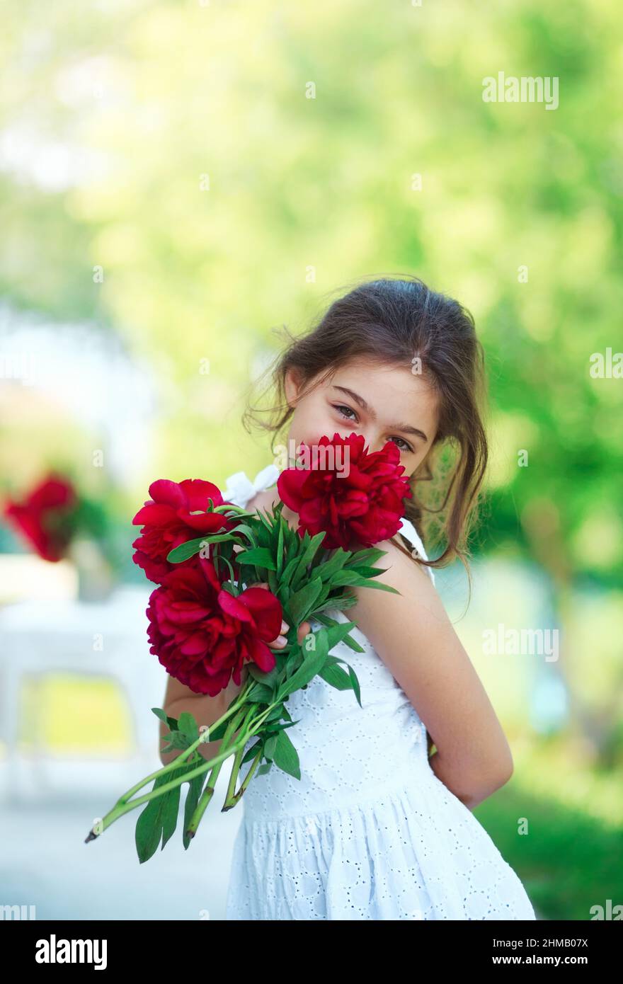 Little cute girl with peony flowers. Child wearing white dress playing ...