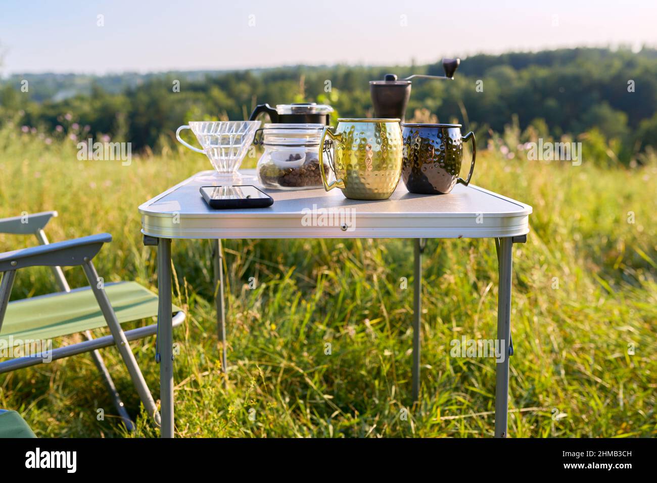 Mugs, grinder, coffee beans on folding table for outdoor camping Stock ...