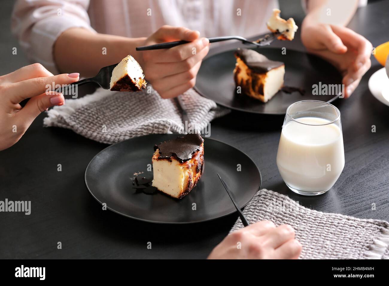 Women eating tasty Basque burnt cheesecake at table Stock Photo - Alamy