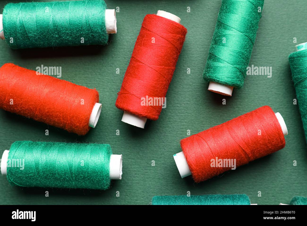 Different sewing threads on green background Stock Photo - Alamy