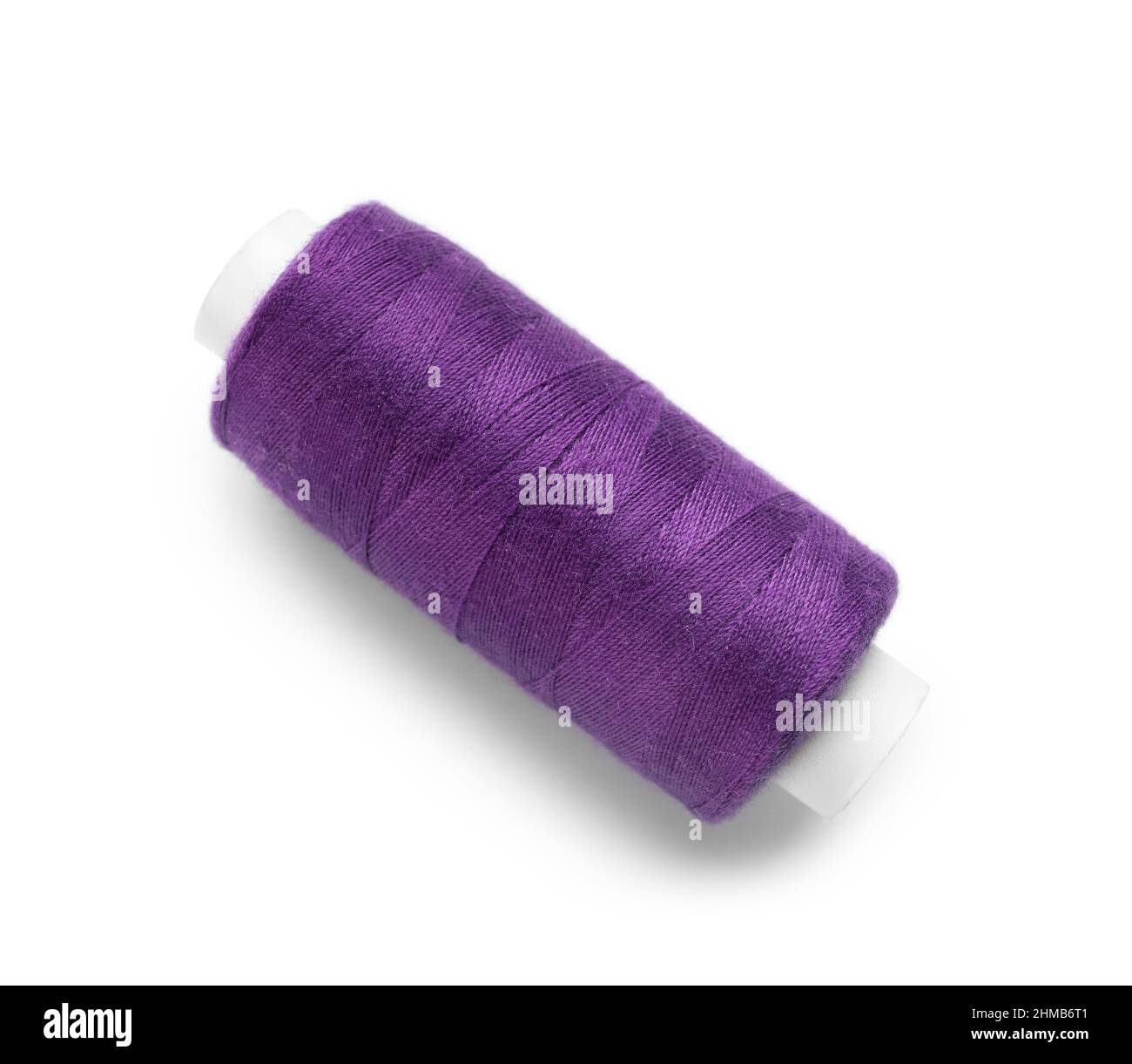 Purple sewing thread spool on white background Stock Photo - Alamy