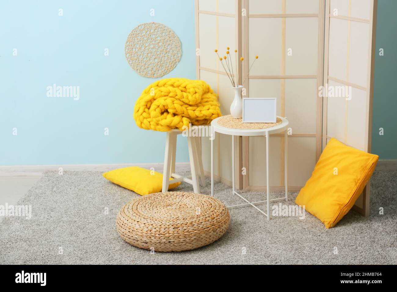 Interior of stylish room with rattan pouf, table and folding screen ...