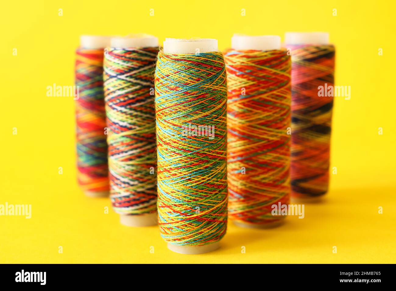 Rainbow sewing thread spools on color background Stock Photo - Alamy
