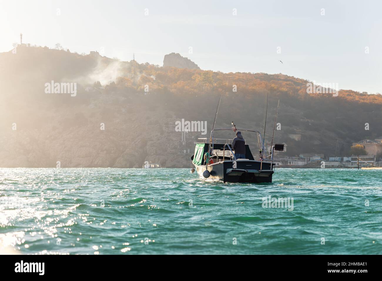 Scenic back view of fisherman angler enjoy fishing with rods on motor ...