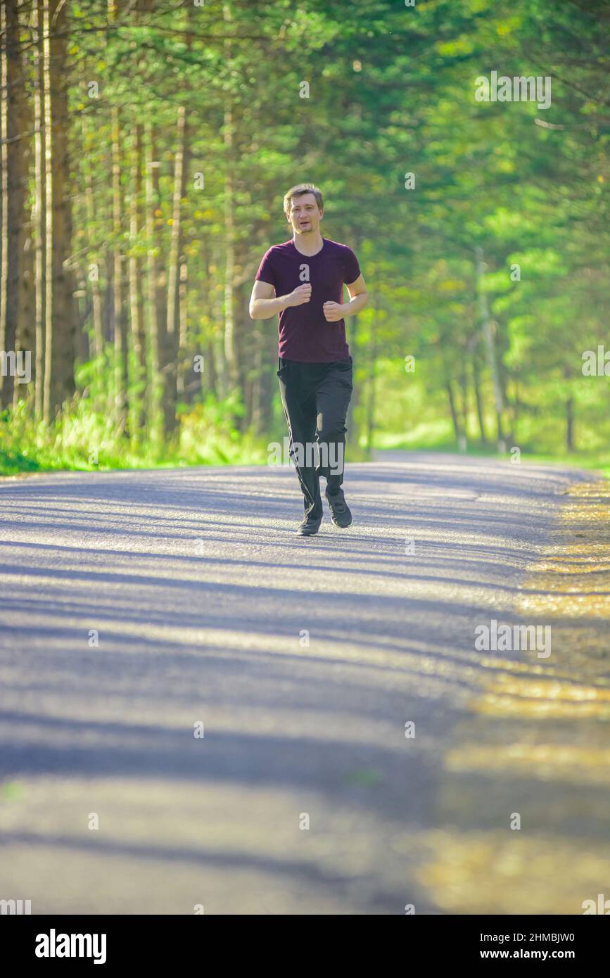 Running man jogging in city park at beautiful summer day. Sport fitness ...