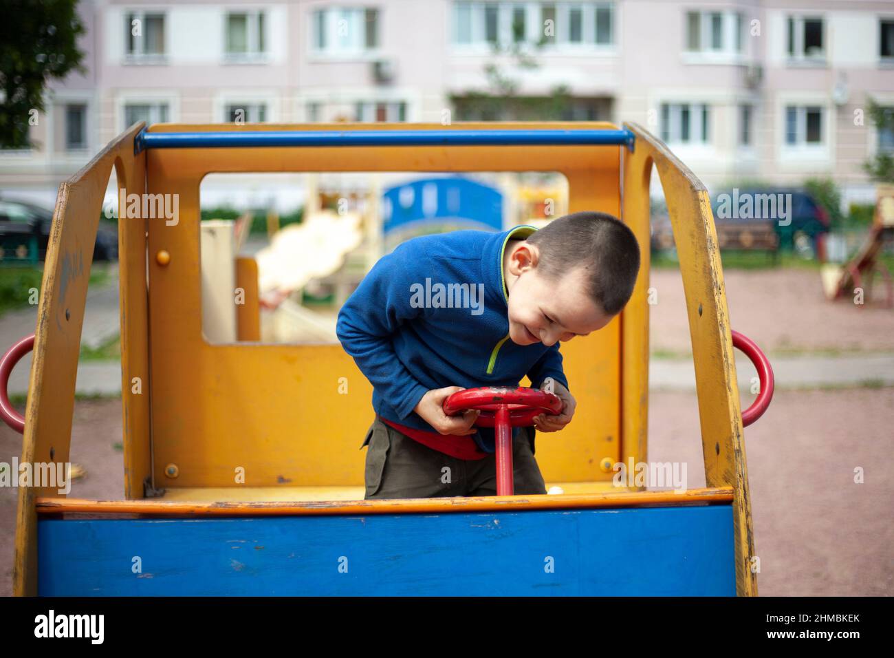 Child on playground. Boy in play area is holding on to wheel of toy ...
