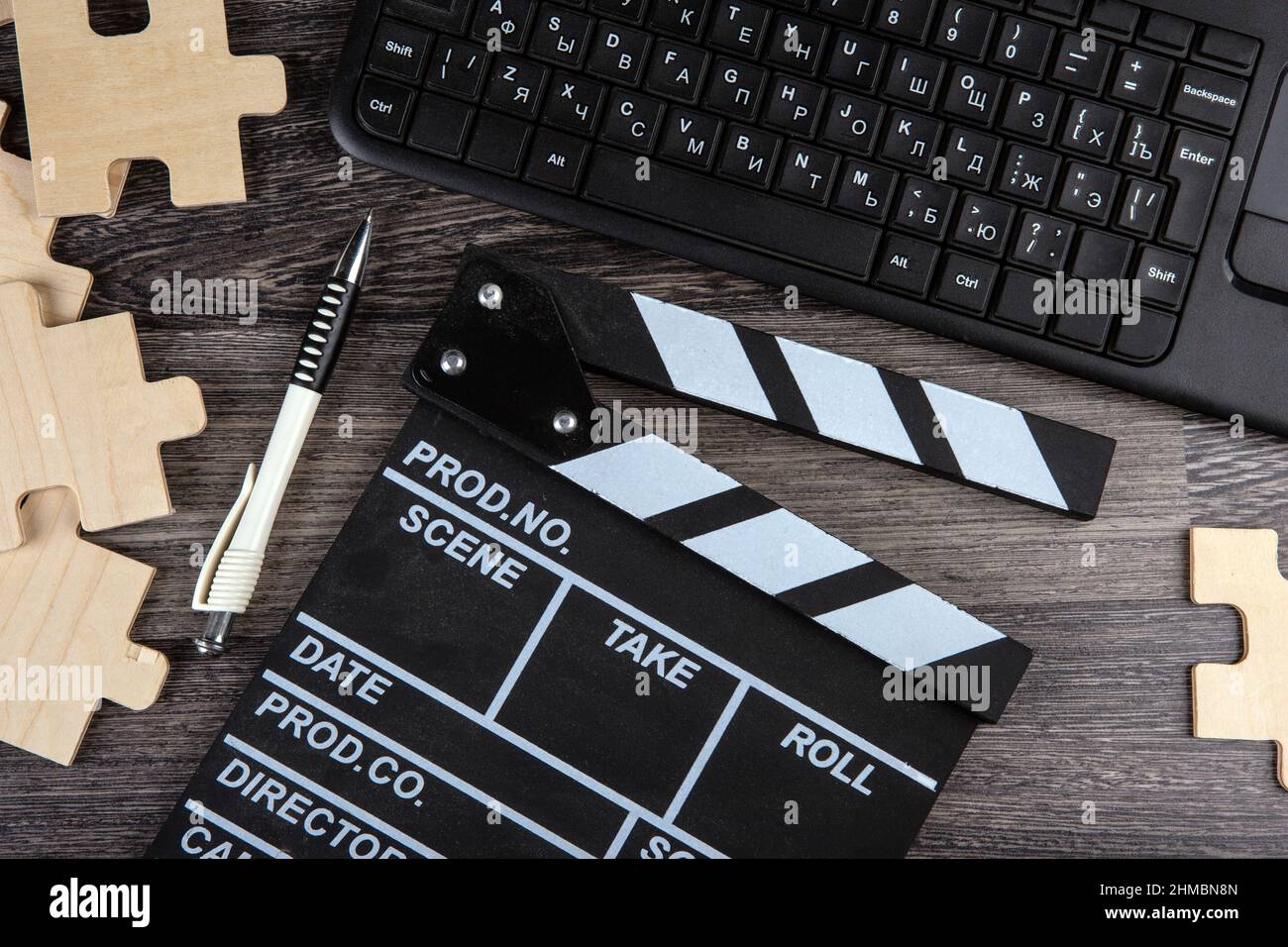 cinematic clapper, pc keyboard, pen and puzzle pieces on a table top ...