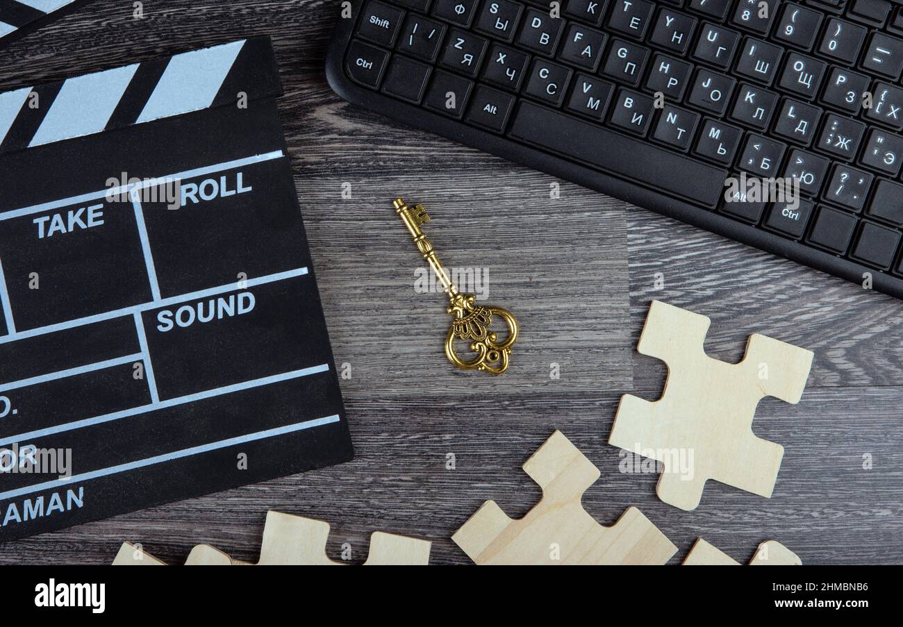 cinematic clapper, pc keyboard, golden key and puzzle pieces on a table ...