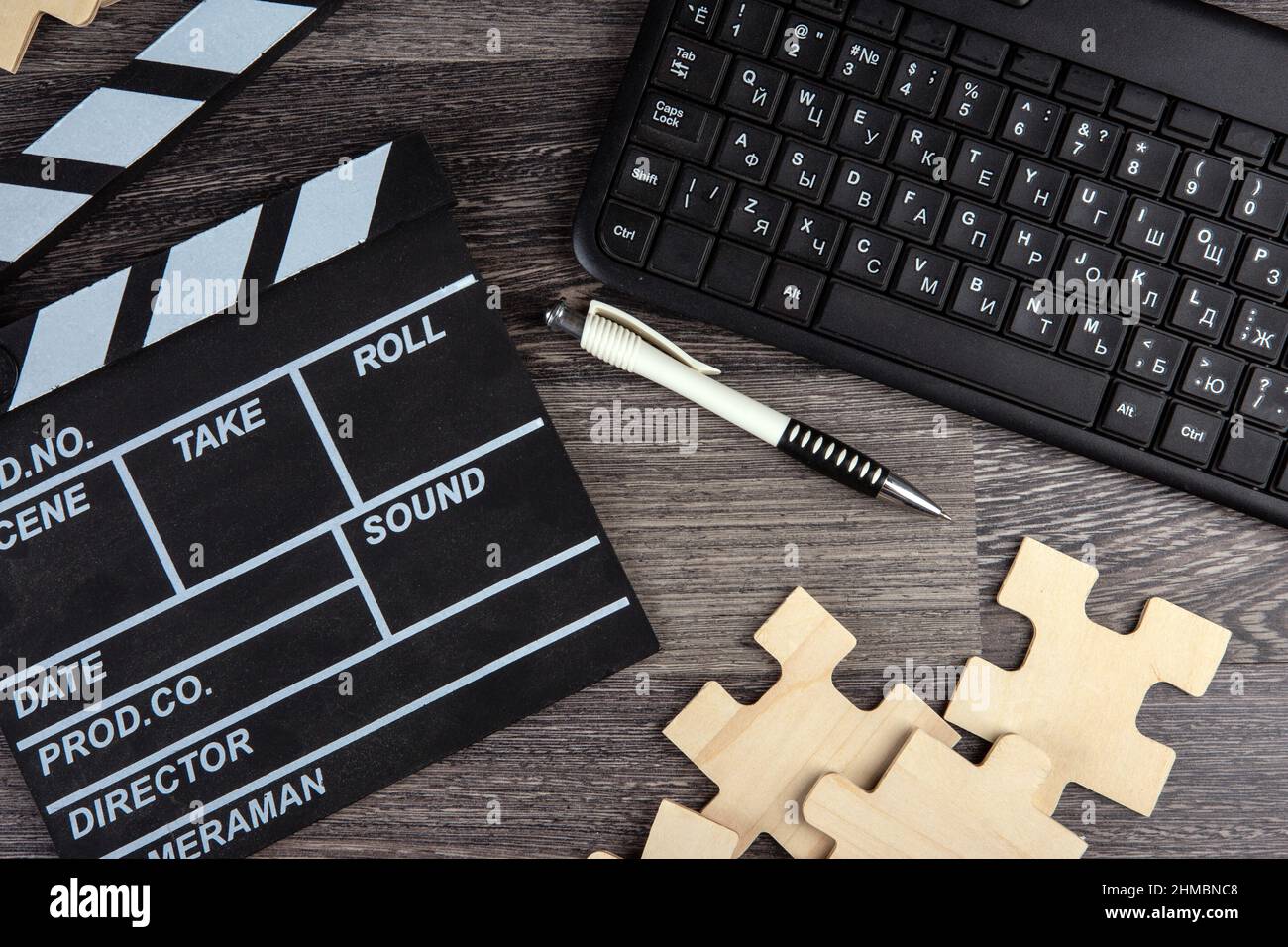 cinematic clapper, pc keyboard, pen and puzzle pieces on a table top ...