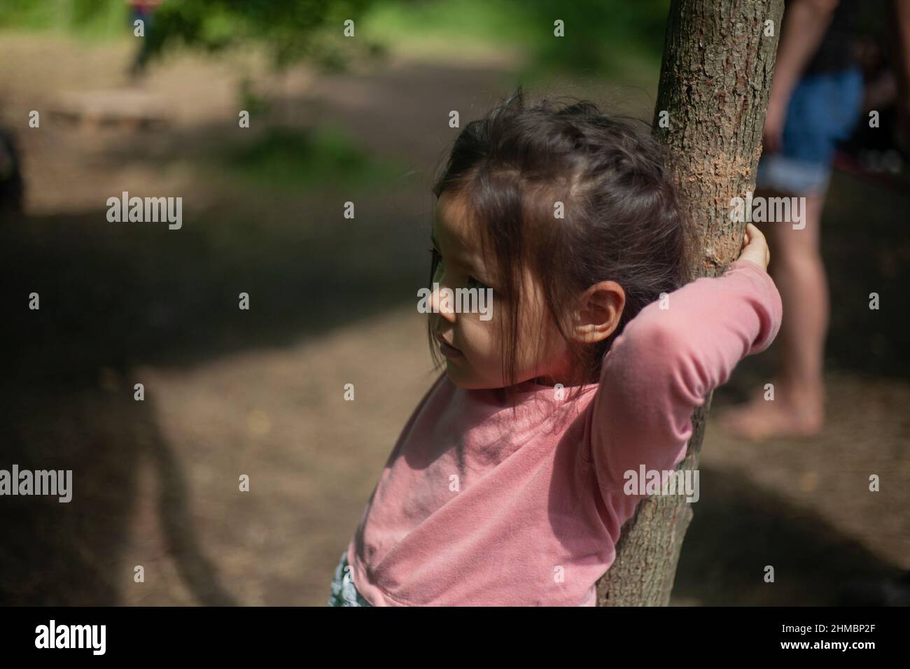 Child rests in nature. Girl with Asian appearance. Child stands leaning ...